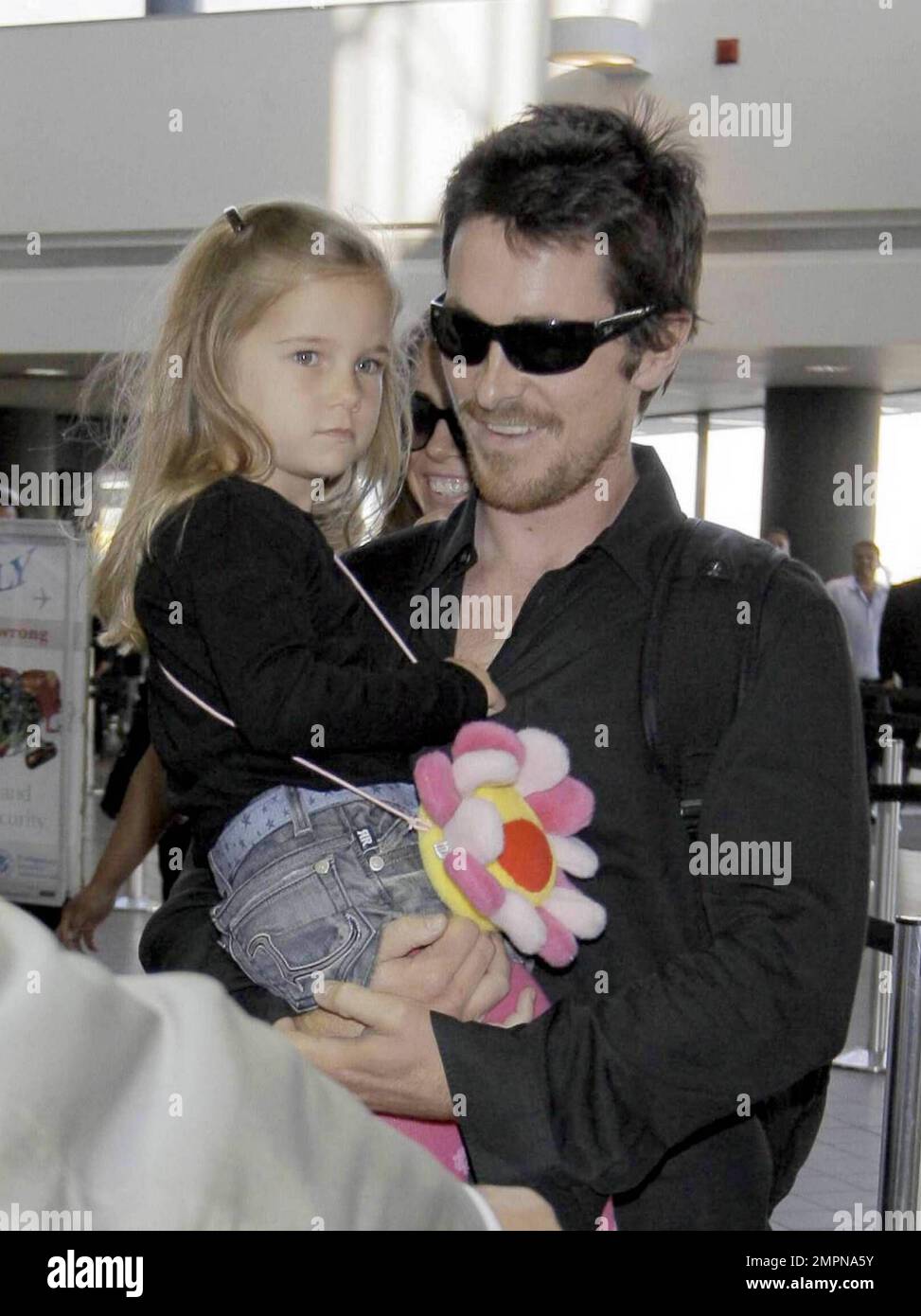 L'acteur Christian Bale porte sa fille Emmeline alors qu'il arrive avec ...