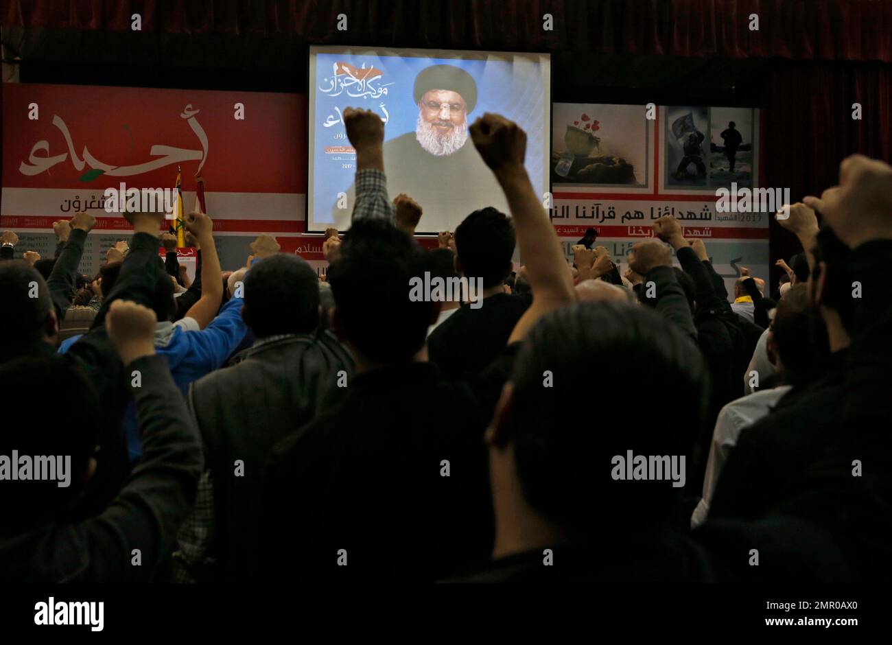 Hezbollah supporters raise their fists and cheer as they listen to a ...