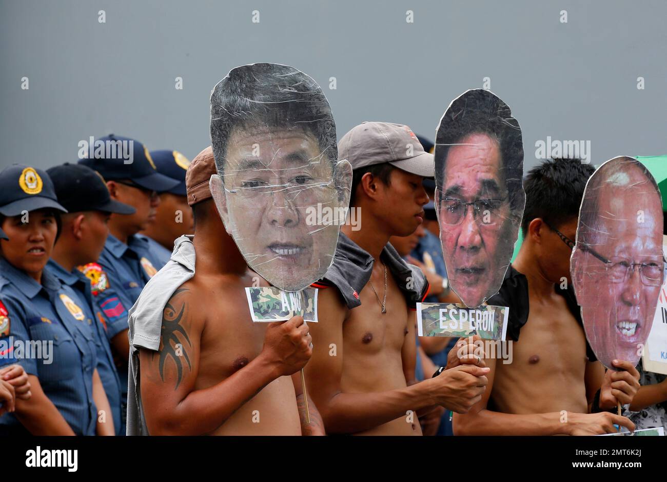 Police officers stand behind protesters displaying portraits of (from ...