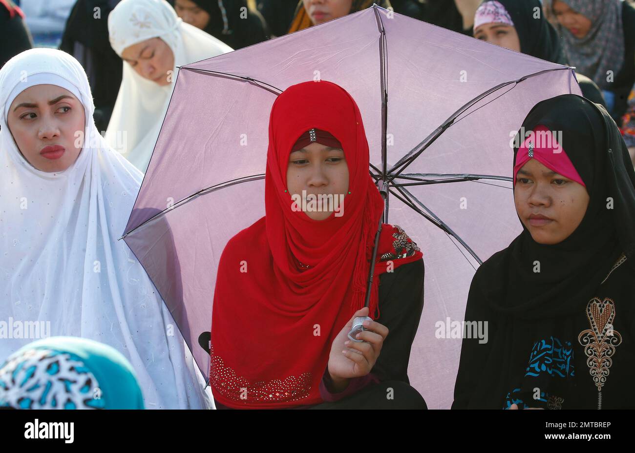 Filipino Muslims shield themselves from the sun as they pray at Manila ...