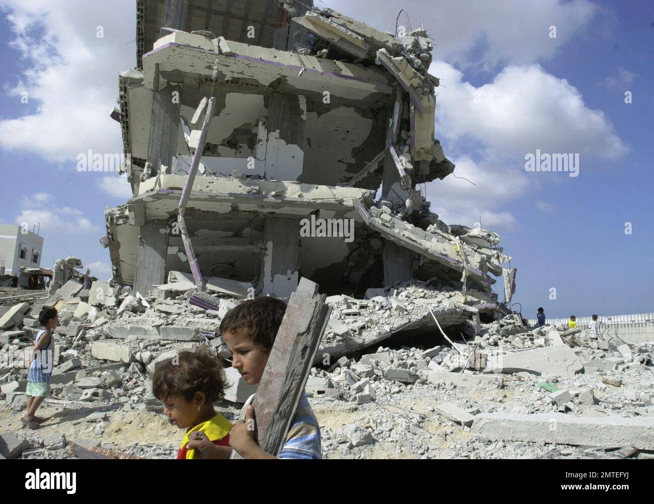 Palestinian children scavenge around the rubble of a five story ...