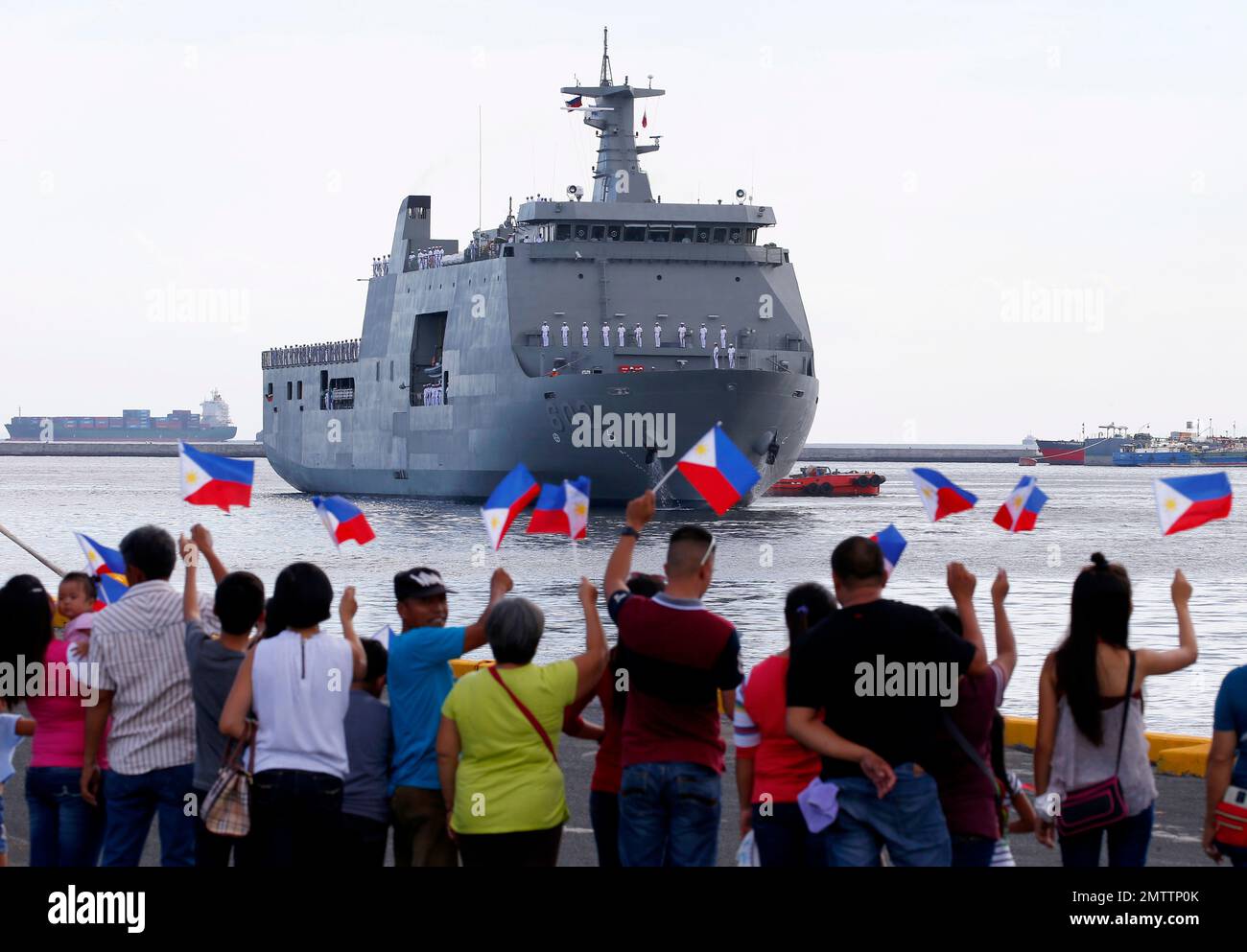 Families of Philippine navy crew wave their country flags to welcome ...