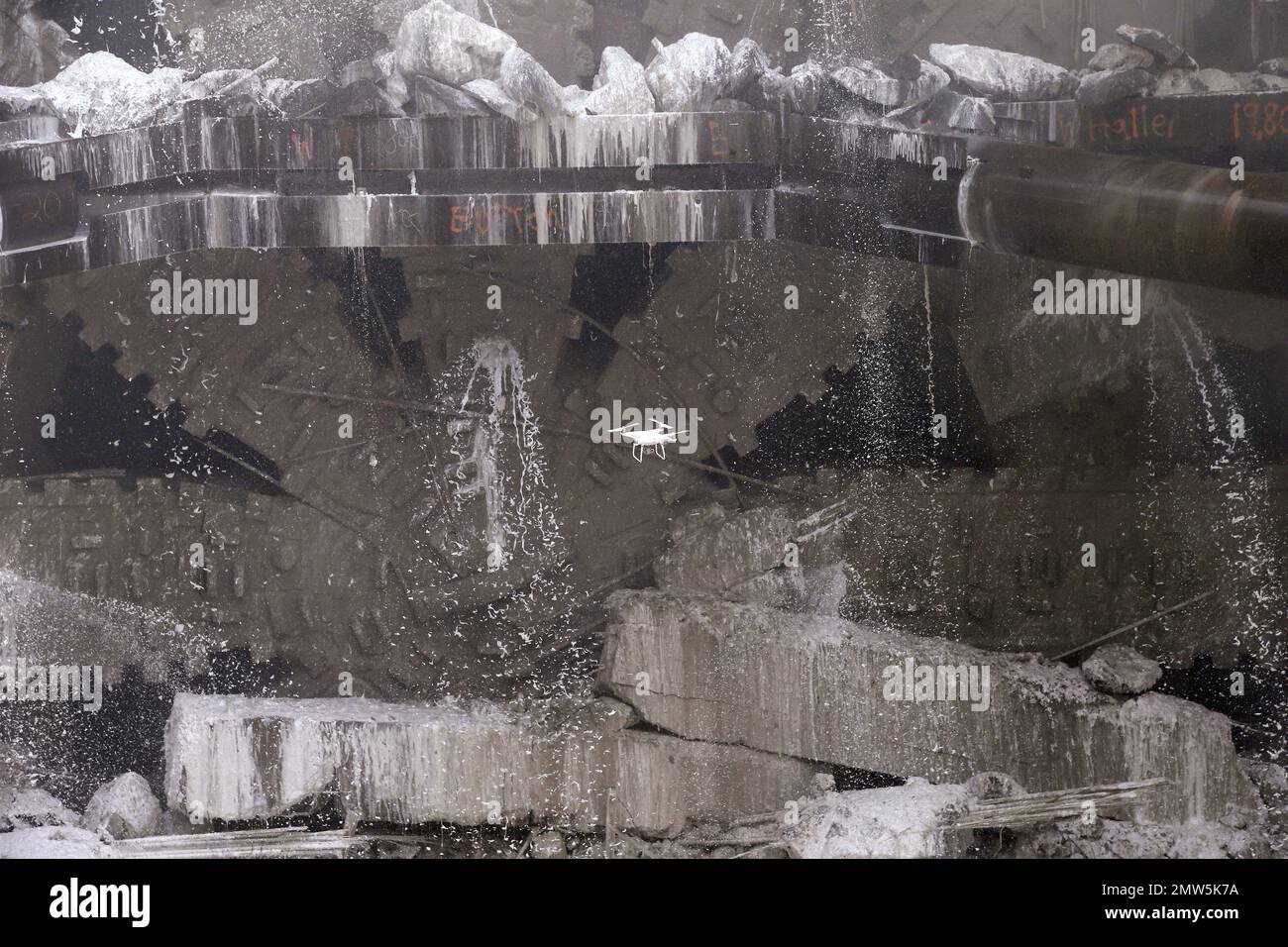 A tiny quadcopter hovers in front of a massive tunneling machine ...