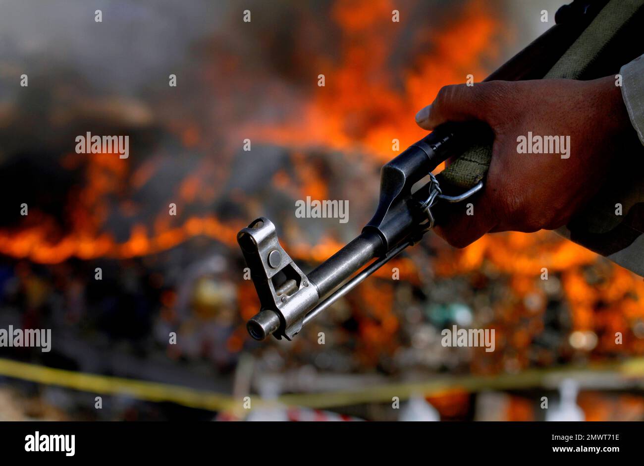 A soldiers from the anti narcotics force stands guard next to burning ...