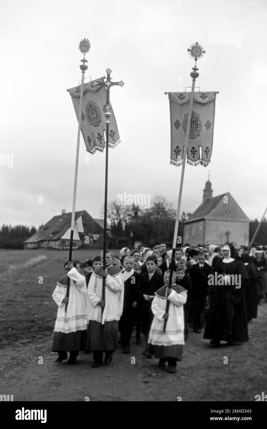 Jungen tragen das Kreuz und die Fahnen BEI Prozession im Schwarzwald zum Todestag des heiligen ...