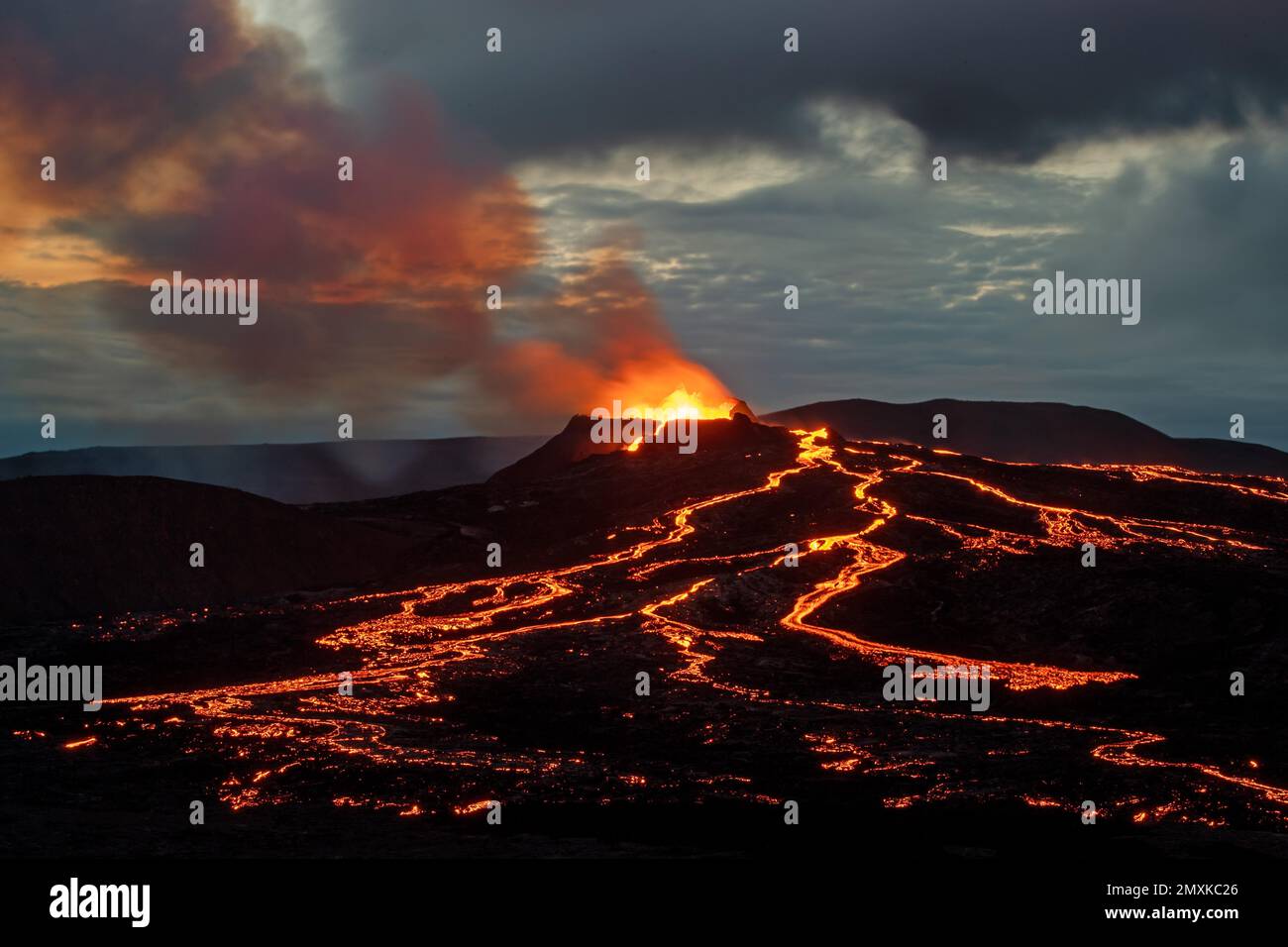 La lave jaillit du cratère et la fumée rougeâtre illuminée, coulées de ...