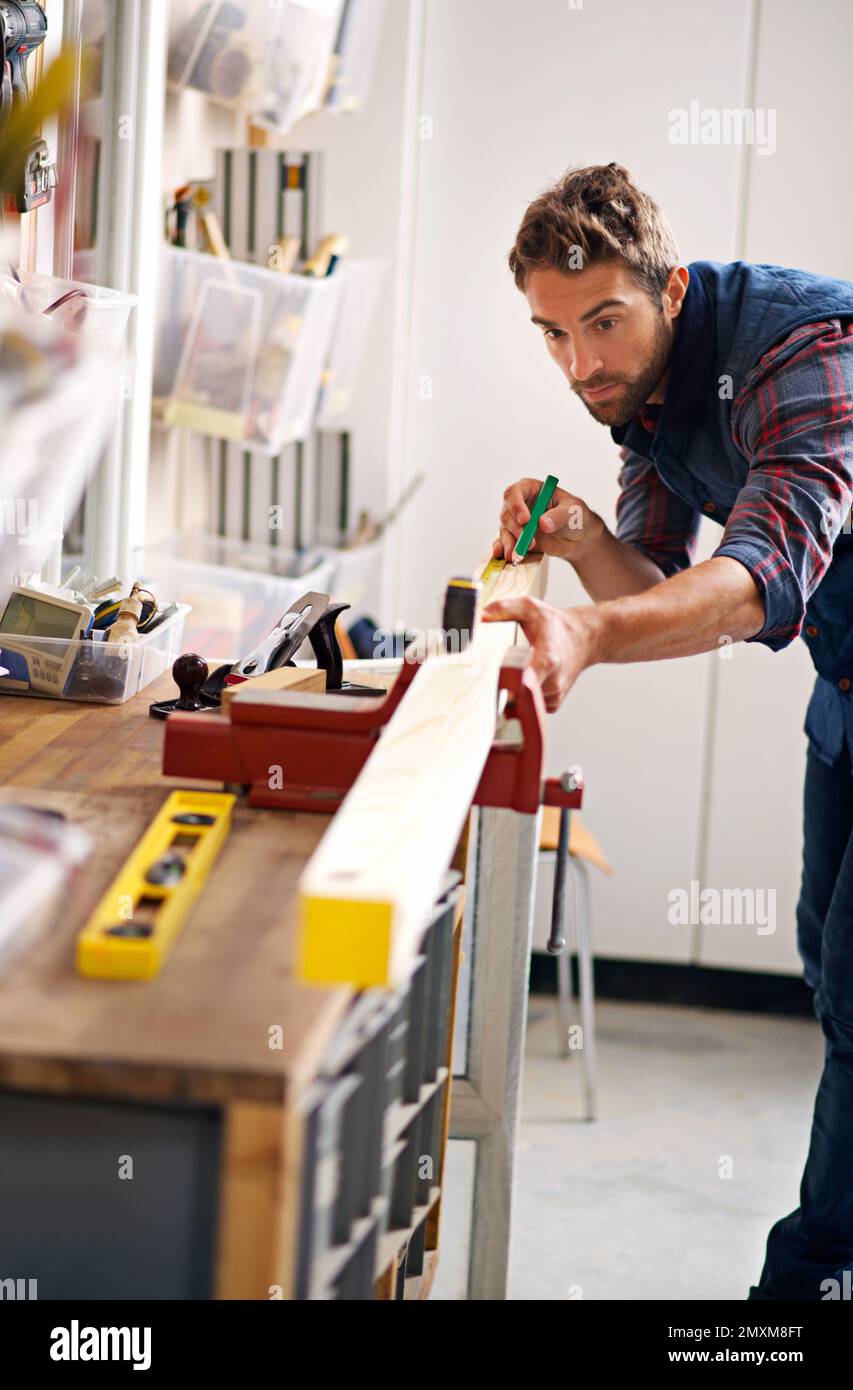 Obtenir ces mesures juste. un beau jeune menuisier mesurant un morceau ...