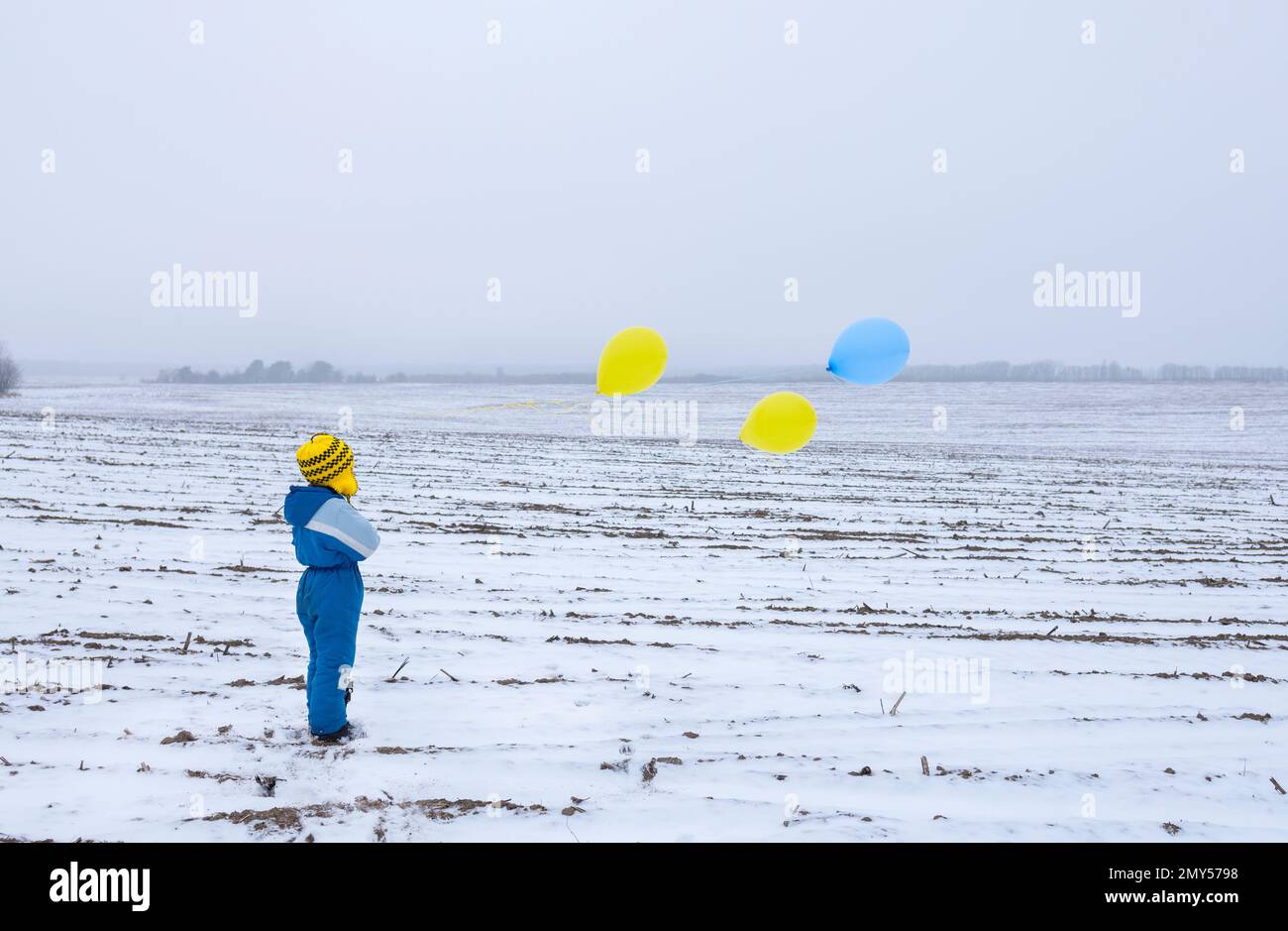 garçon solitaire méconnaissable debout sur un terrain enneigé et ...
