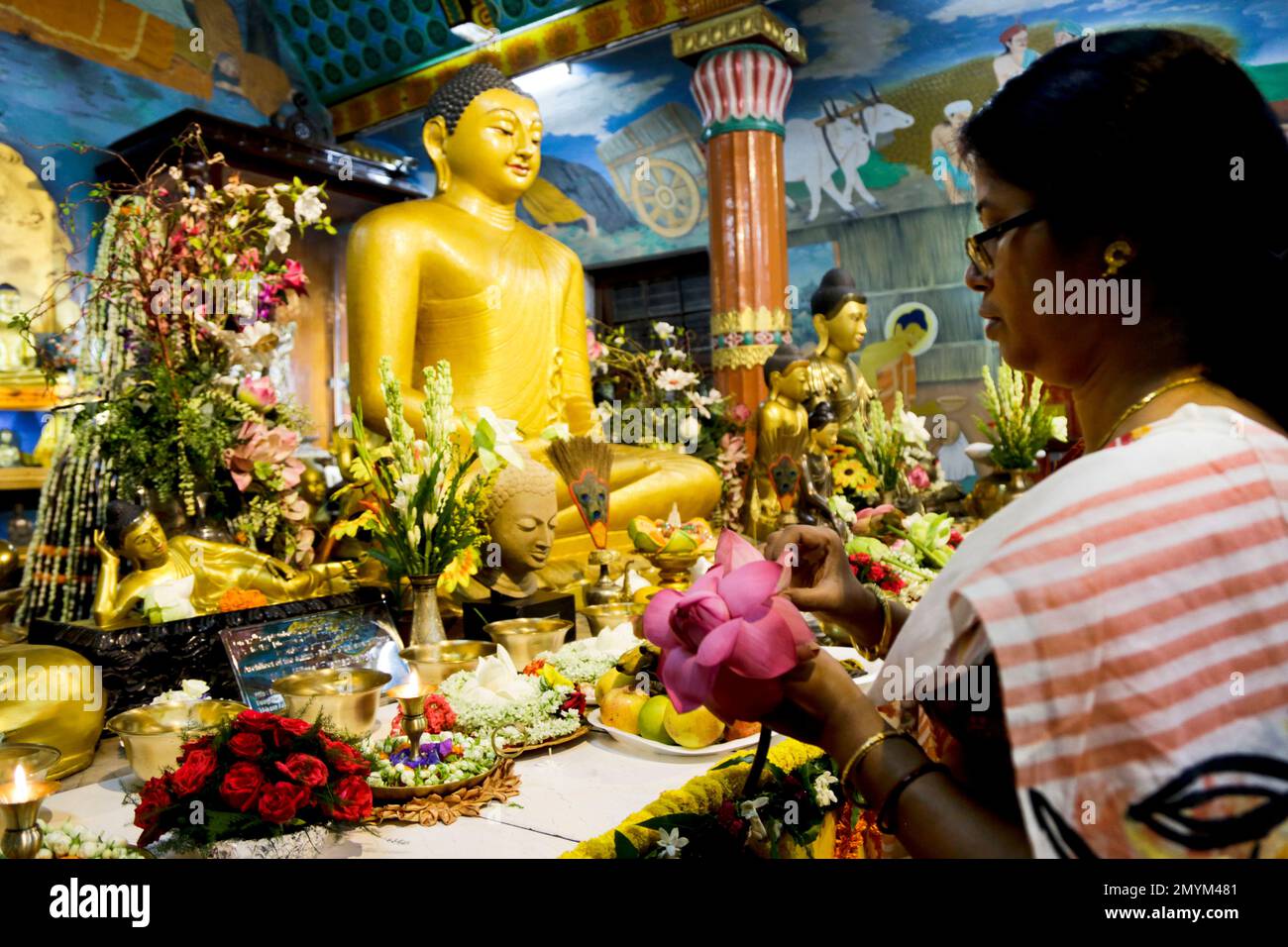 A devotee offer flowers to Buddha statues at a temple during Buddha ...