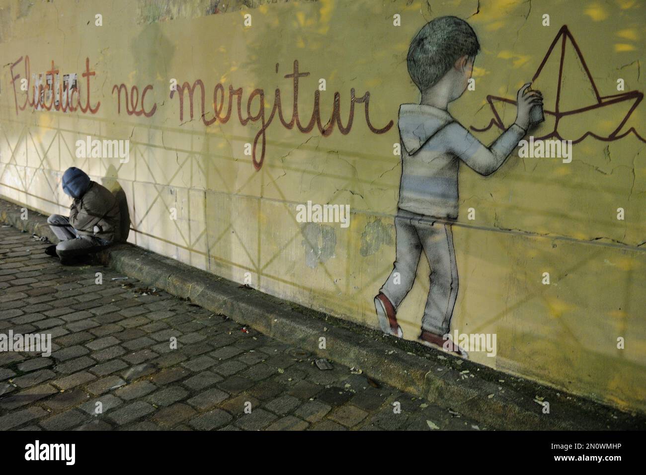 In this photo taken on Monday Nov. 23, 2015 in Paris, a child sits by a ...