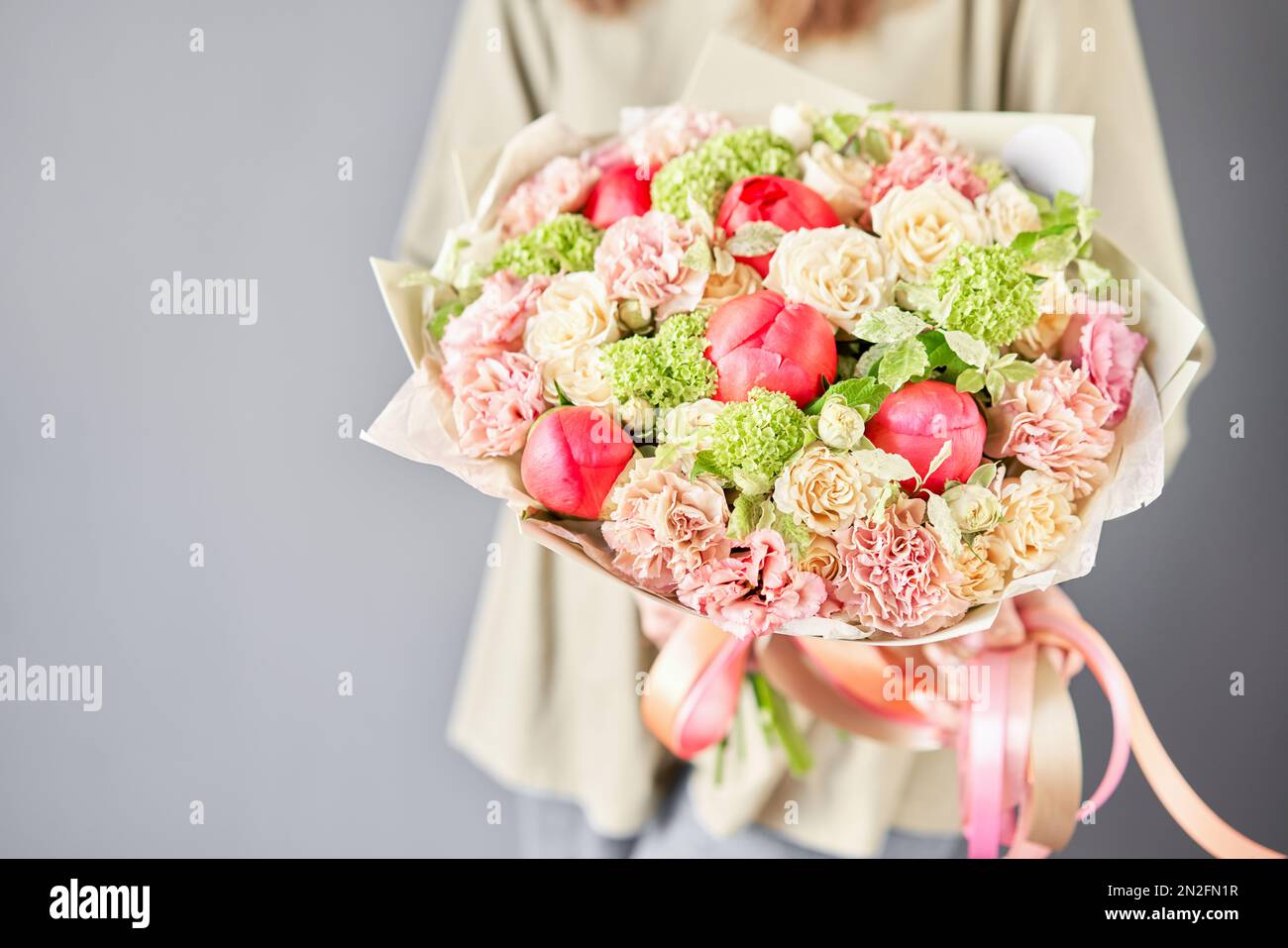 La fleuriste crée un beau bouquet de fleurs mixtes avec des œillets ...