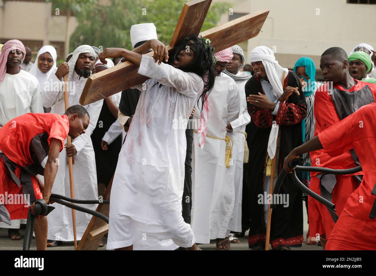 A man dressed as Jesus Christ carries a wooden cross during a ritual ...