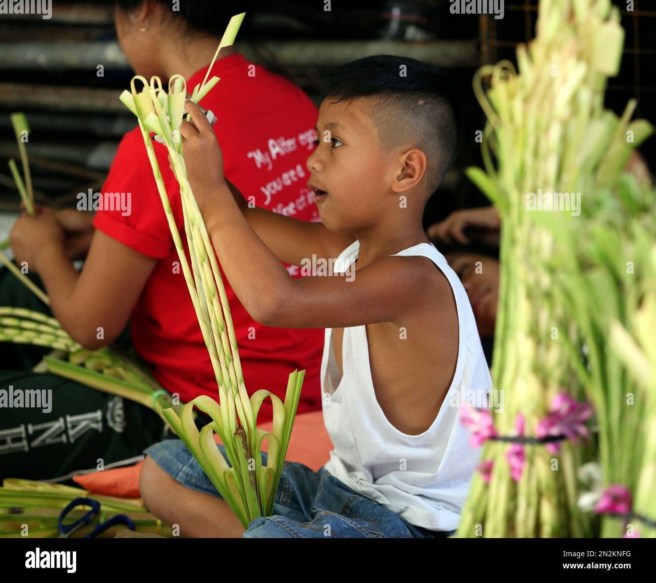 A boy crafts palm fronds to be blessed for Palm Sunday rites among ...