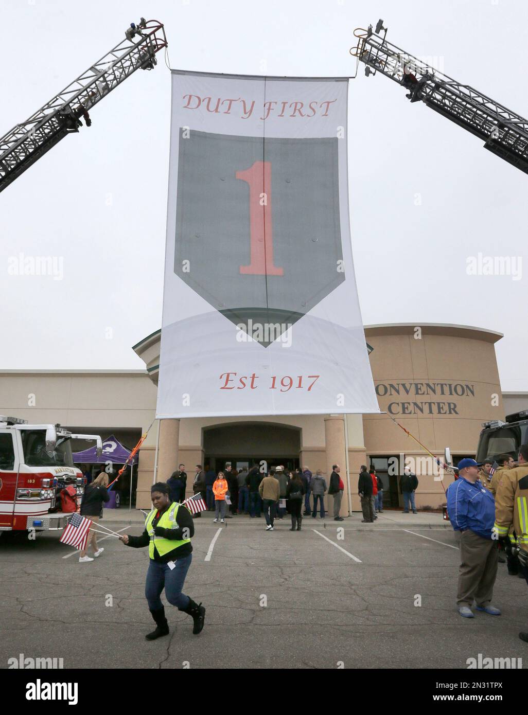 A 1st Infantry Division banner is suspended by ladder trucks provided ...