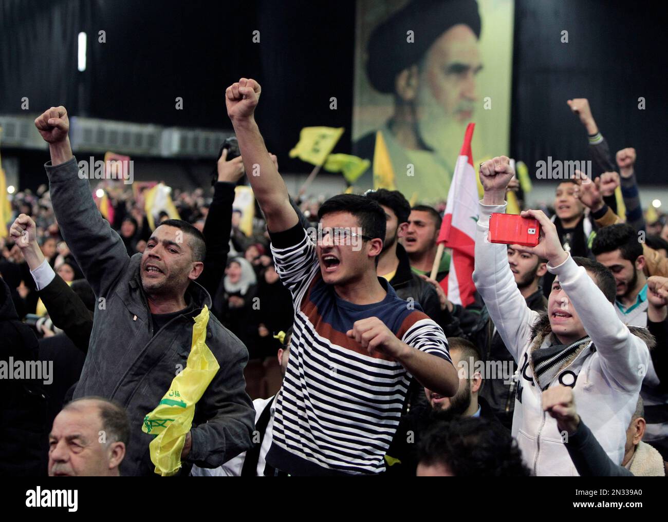 Hezbollah supporters raise their hands in salute as their leader Sheikh ...