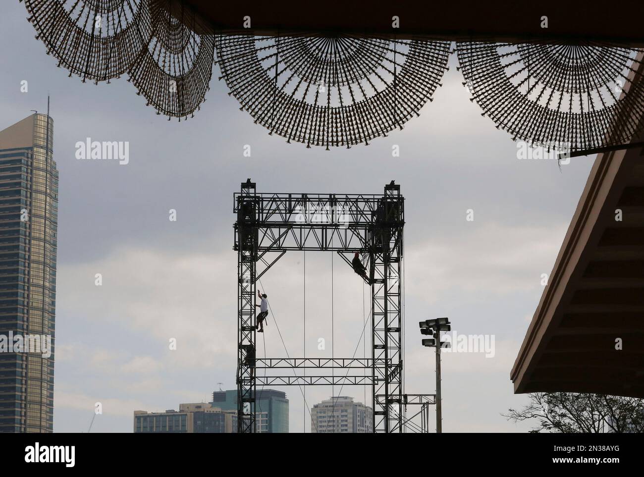 A Filipino worker scales a tower to set up lights and speakers to be ...
