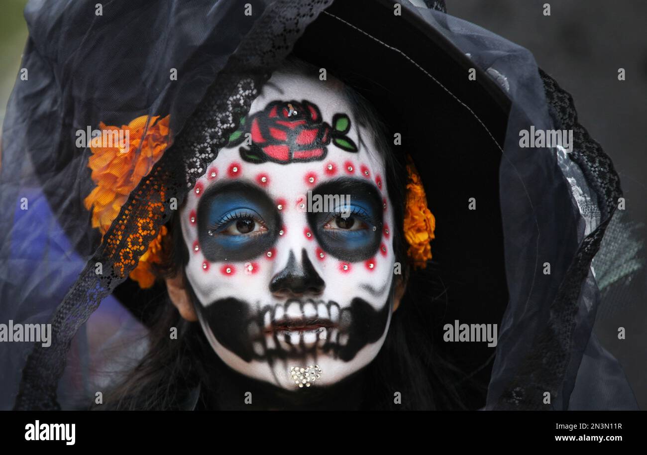 A woman dressed as the iconic Mexican "Catrina" poses for photographers ...