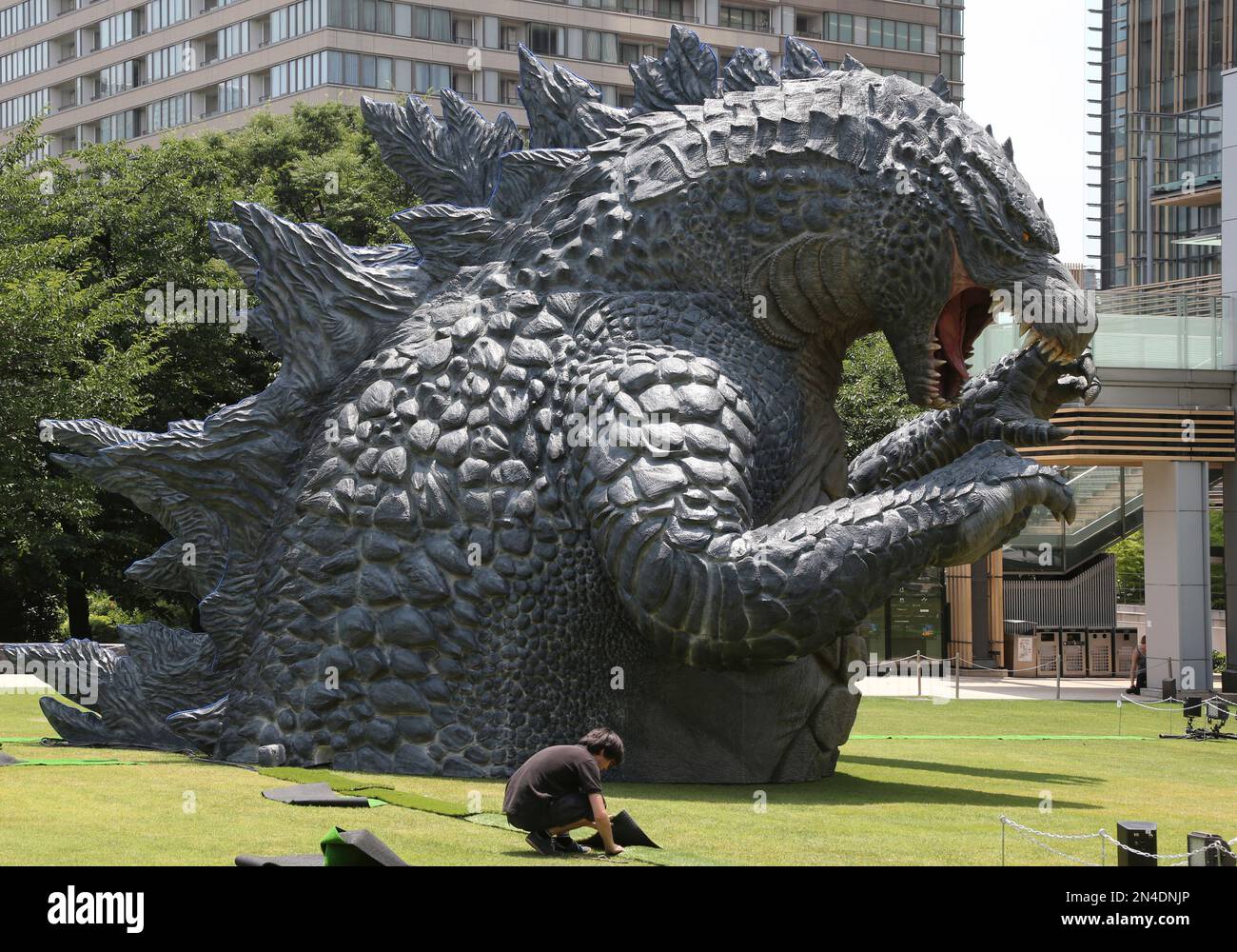 A scaled down model of the new "Godzilla," dwarfs a worker at Tokyo ...