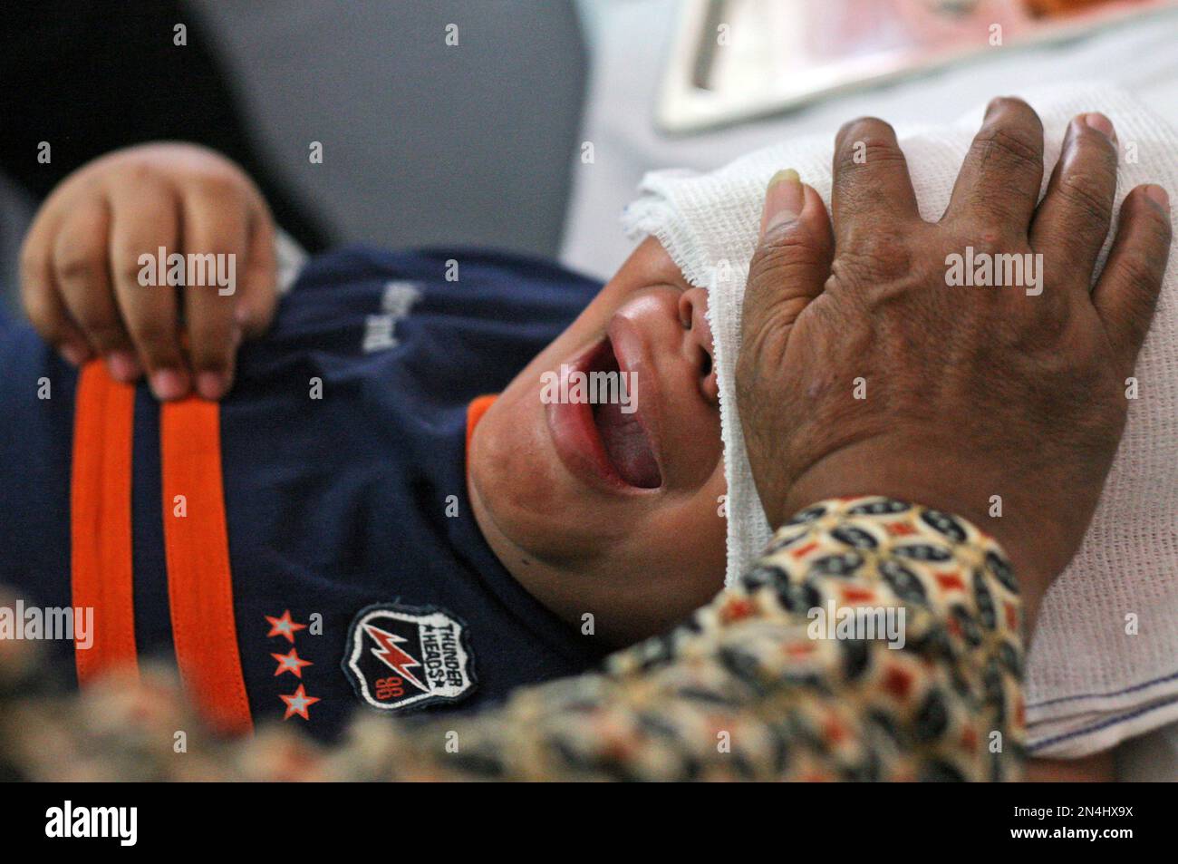 A crying boy is comforted by a family member as he is being circumcised ...