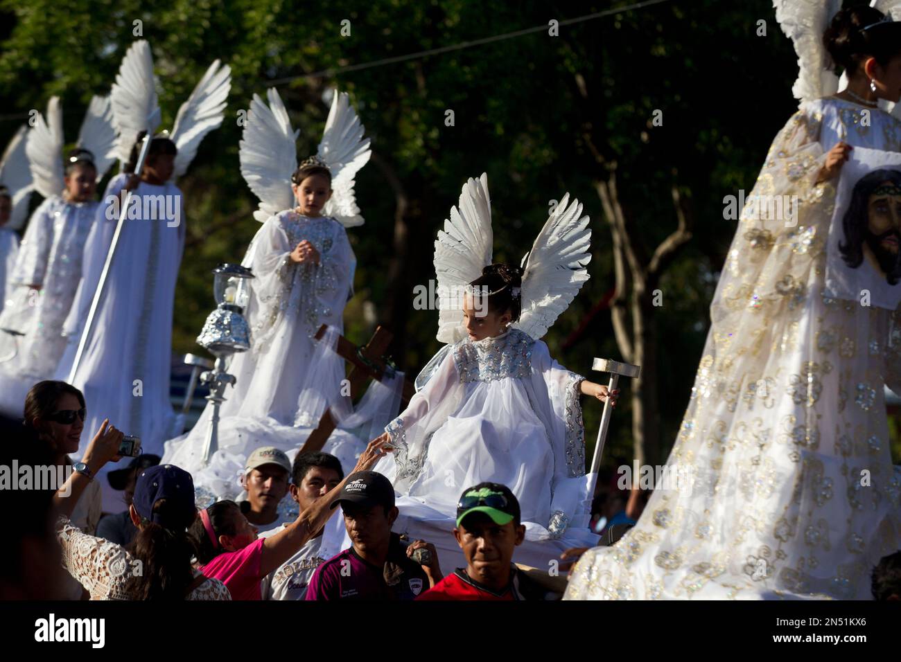 Girls dressed as angels stand on platforms as they are carried in a ...