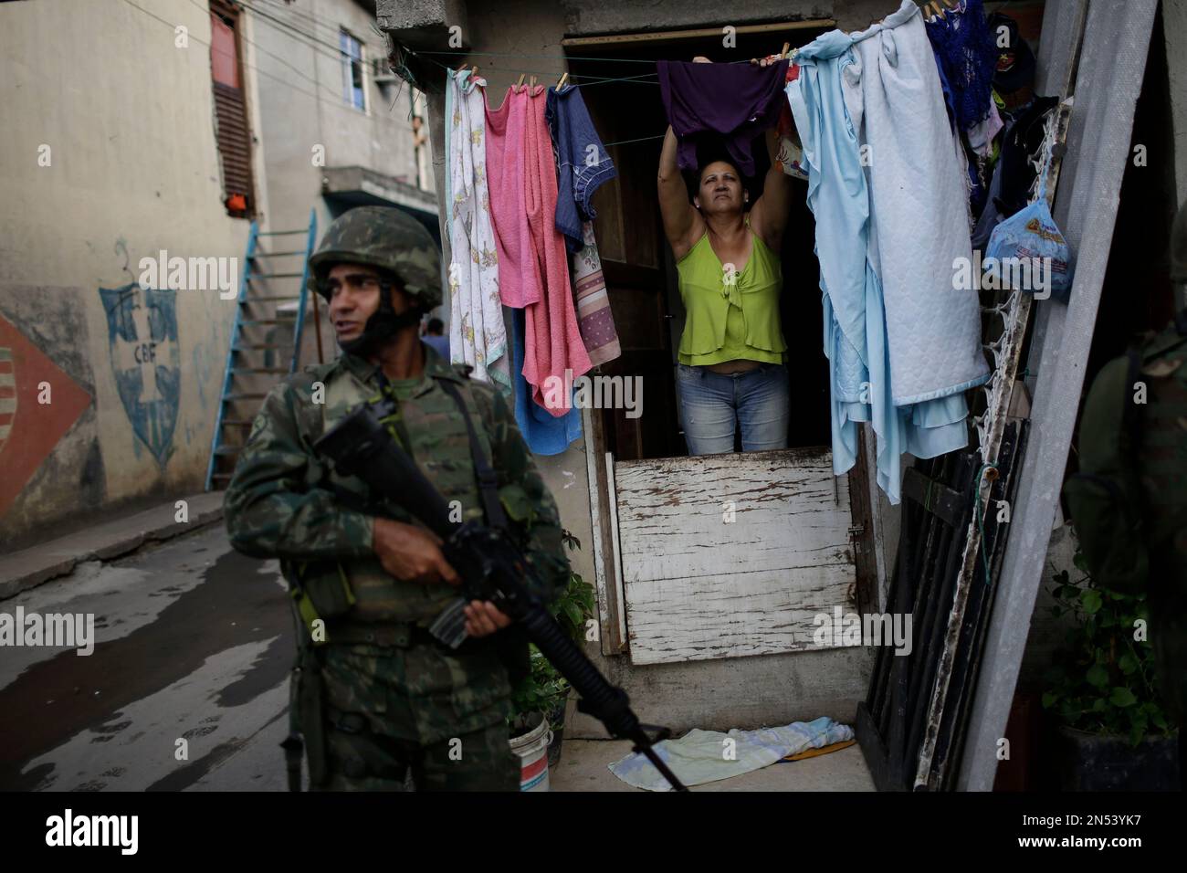 A woman hangs clothes to dry while a navy soldier enters to occupy the ...
