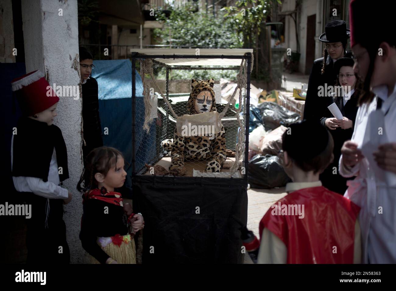 An ultra-Orthodox Jewish girl wearing a costume, sits in a cage ...