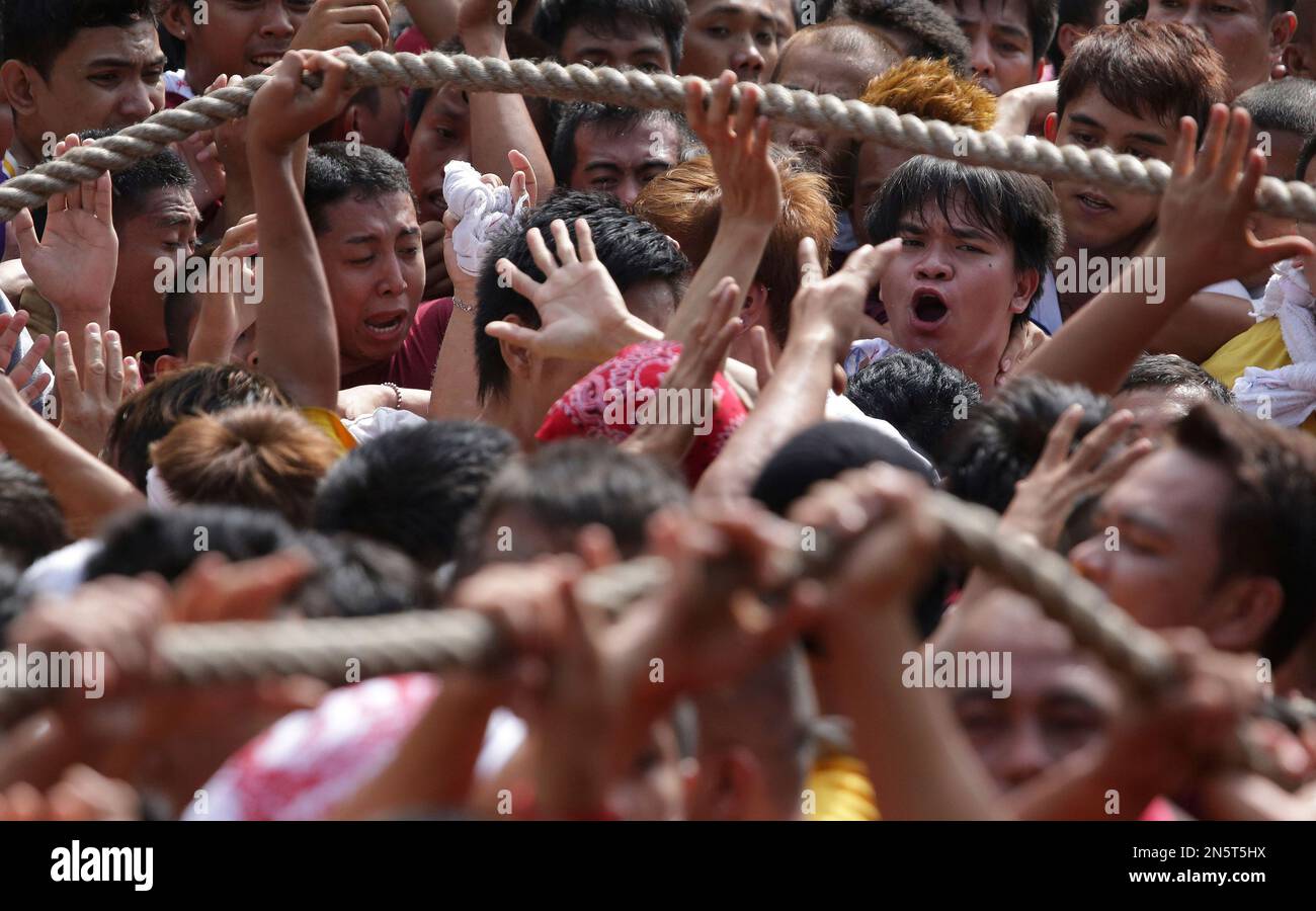 Filipino Catholic devotees jostle to hold the rope of the carriage of ...