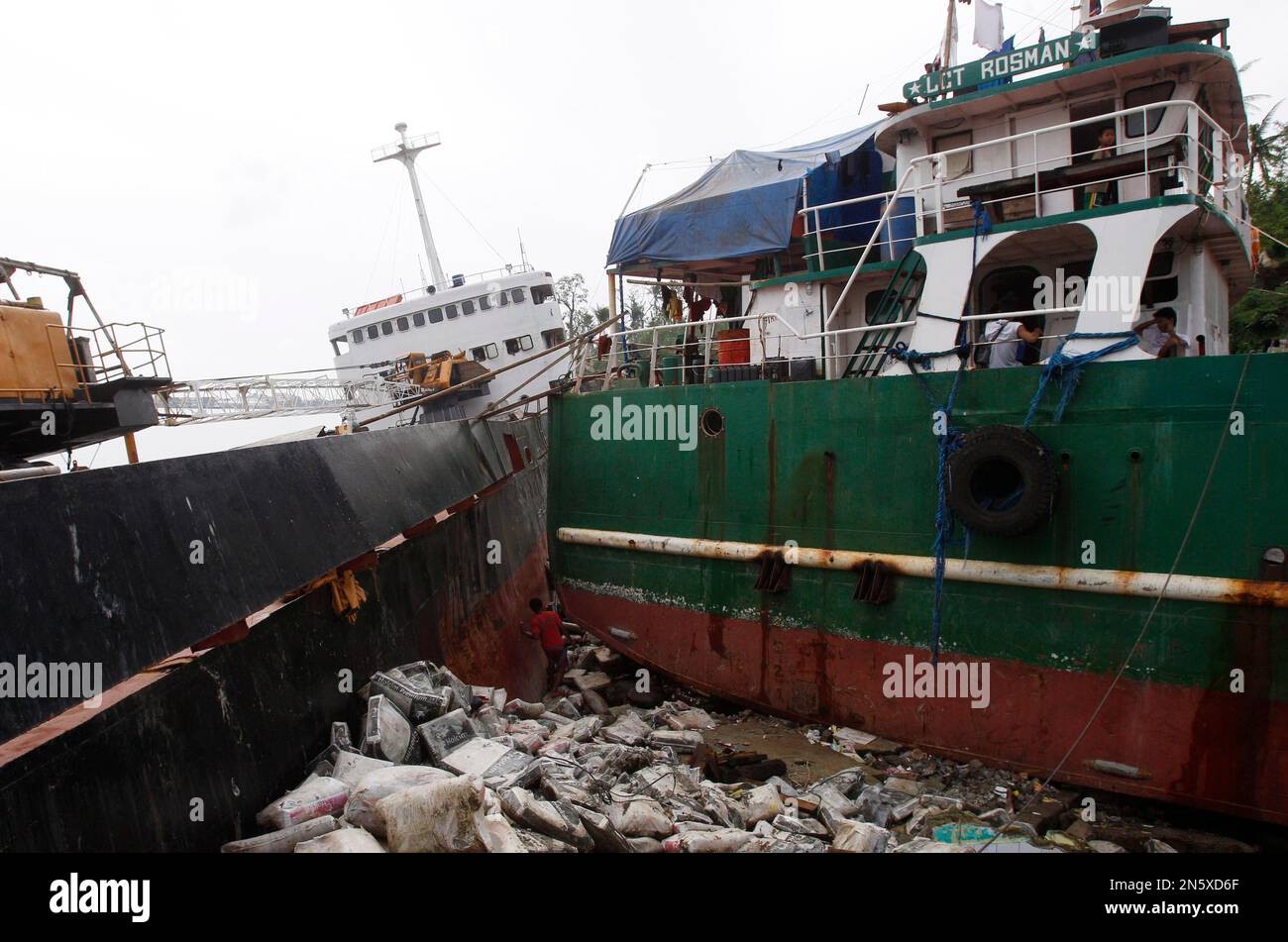 A typhoon survivor walks in the middle of shipping vessels that remain ...
