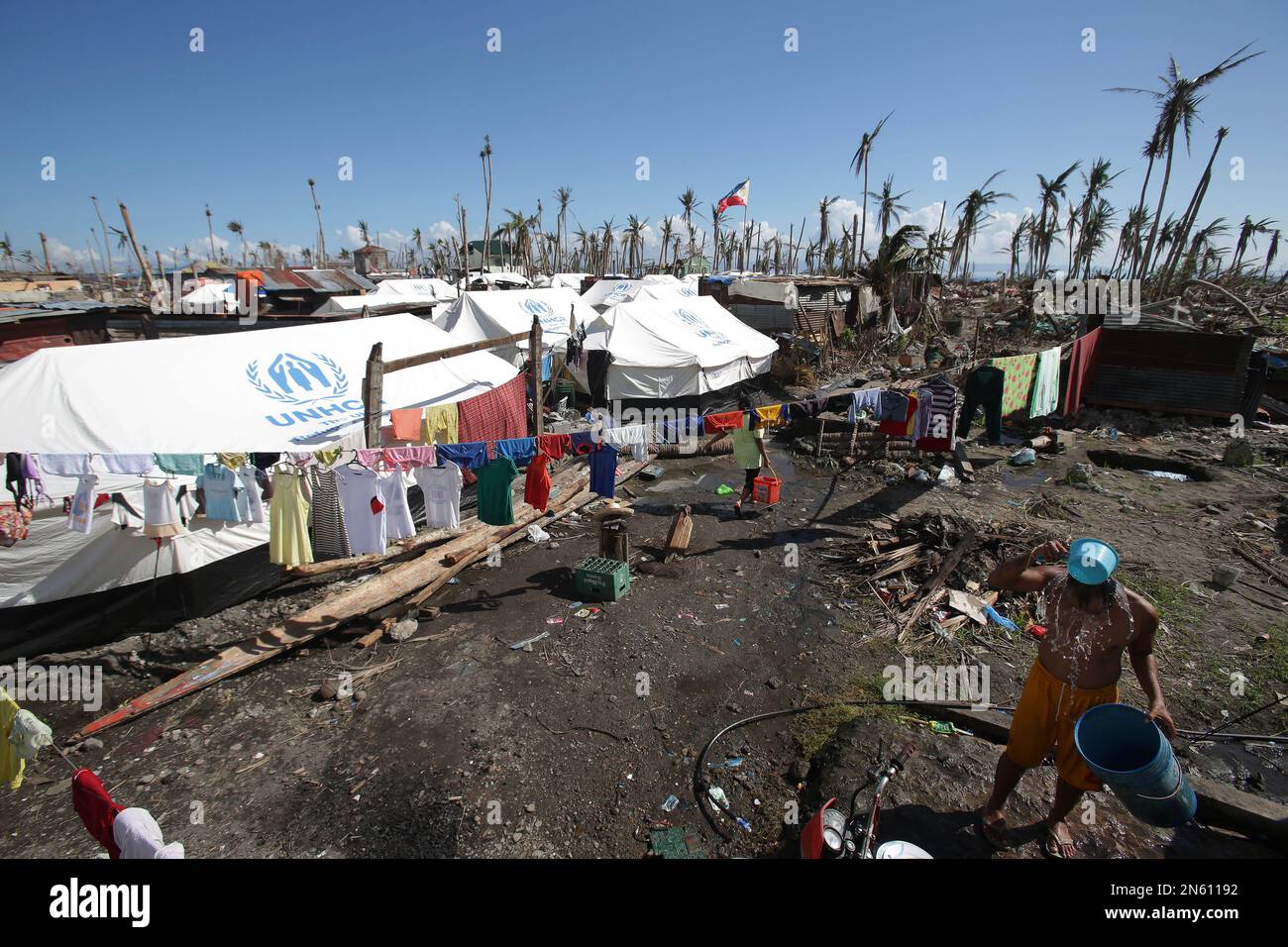A typhoon survivor takes a bath beside donated tents at typhoon-ravaged ...