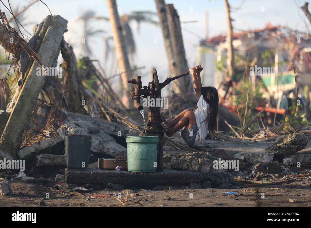 A young typhoon survivor fetches water from a hand pump at typhoon ...