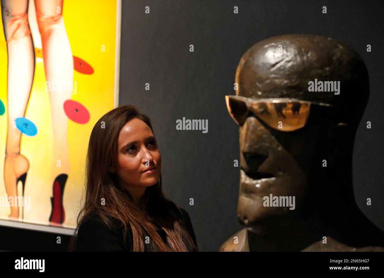An auction house worker poses for photographers as she inspects a work ...