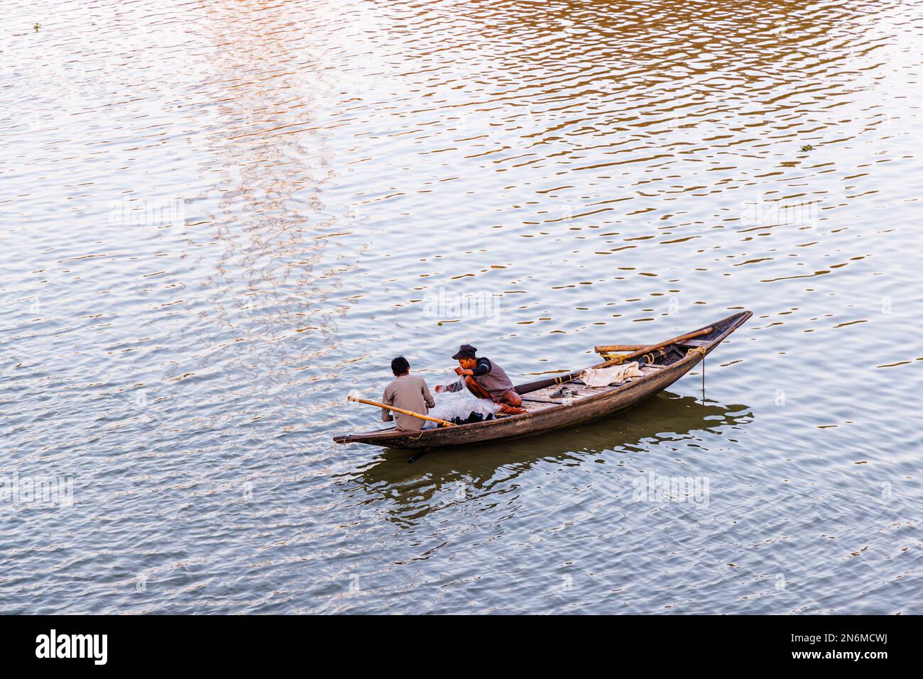 Pêcheurs locaux pêchant avec des filets d'un petit bateau à rames en ...