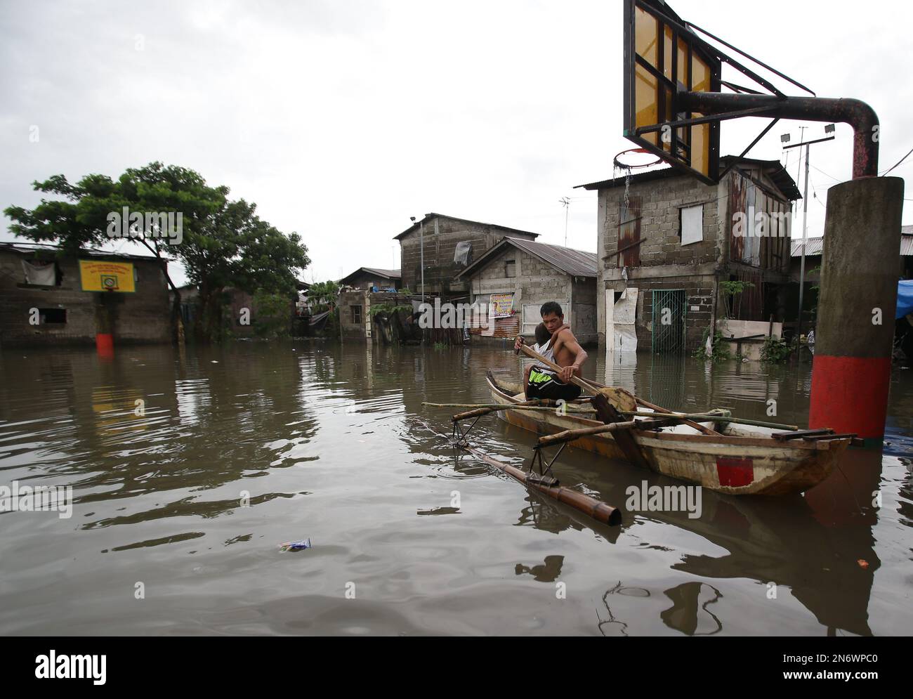 A Filipino man and his daughter ride a small boat on a flooded ...