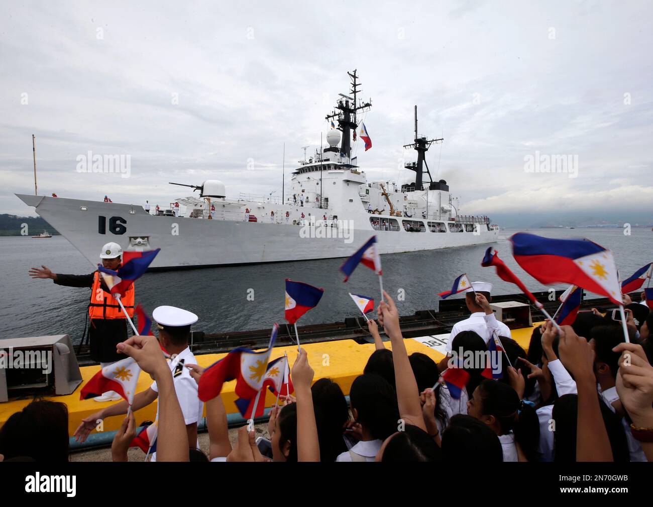 Students and other guests wave Philippine flags to welcome the second ...