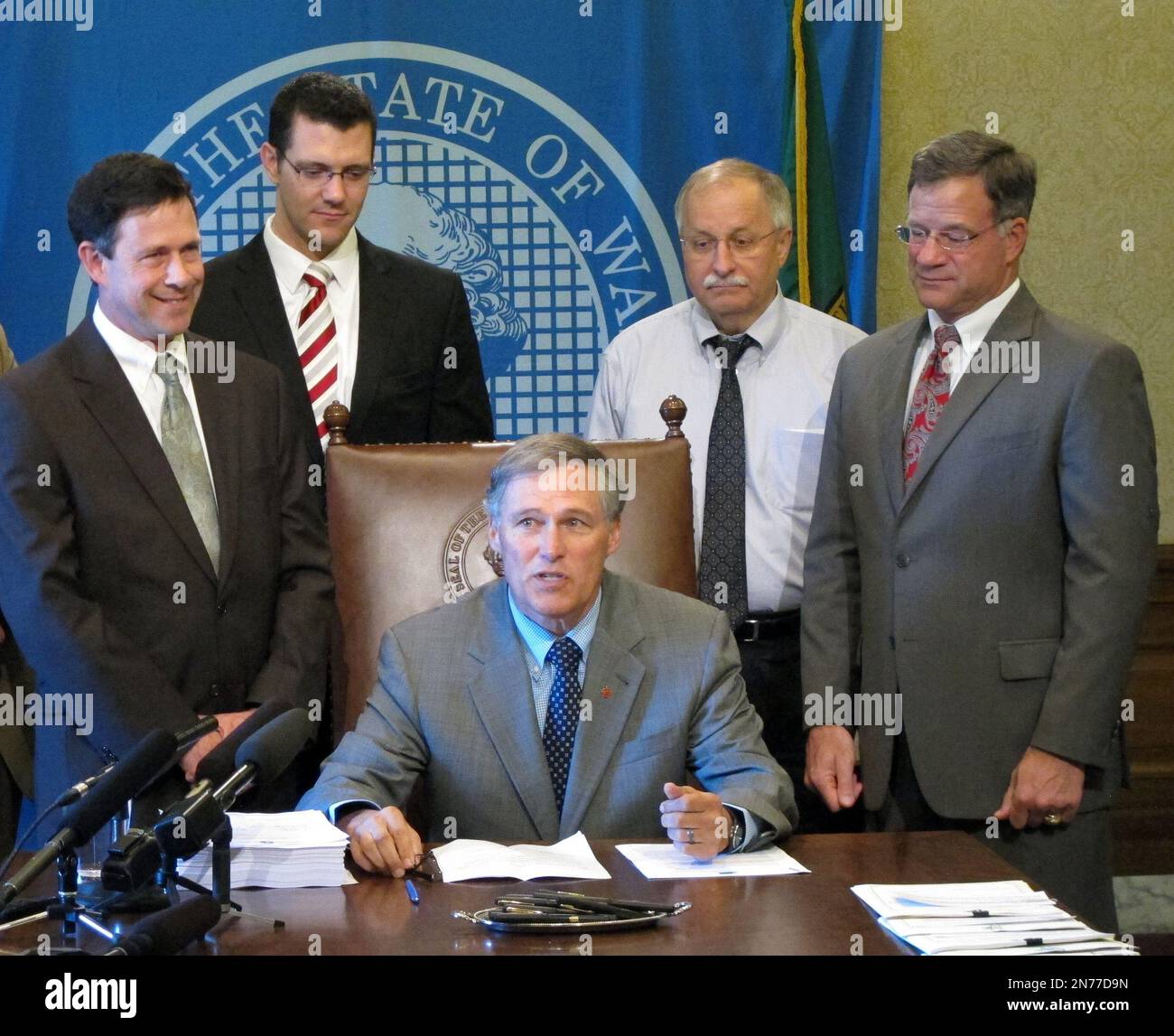Gov. Jay Inslee, seated, prepares to sign a new state budget as, from ...