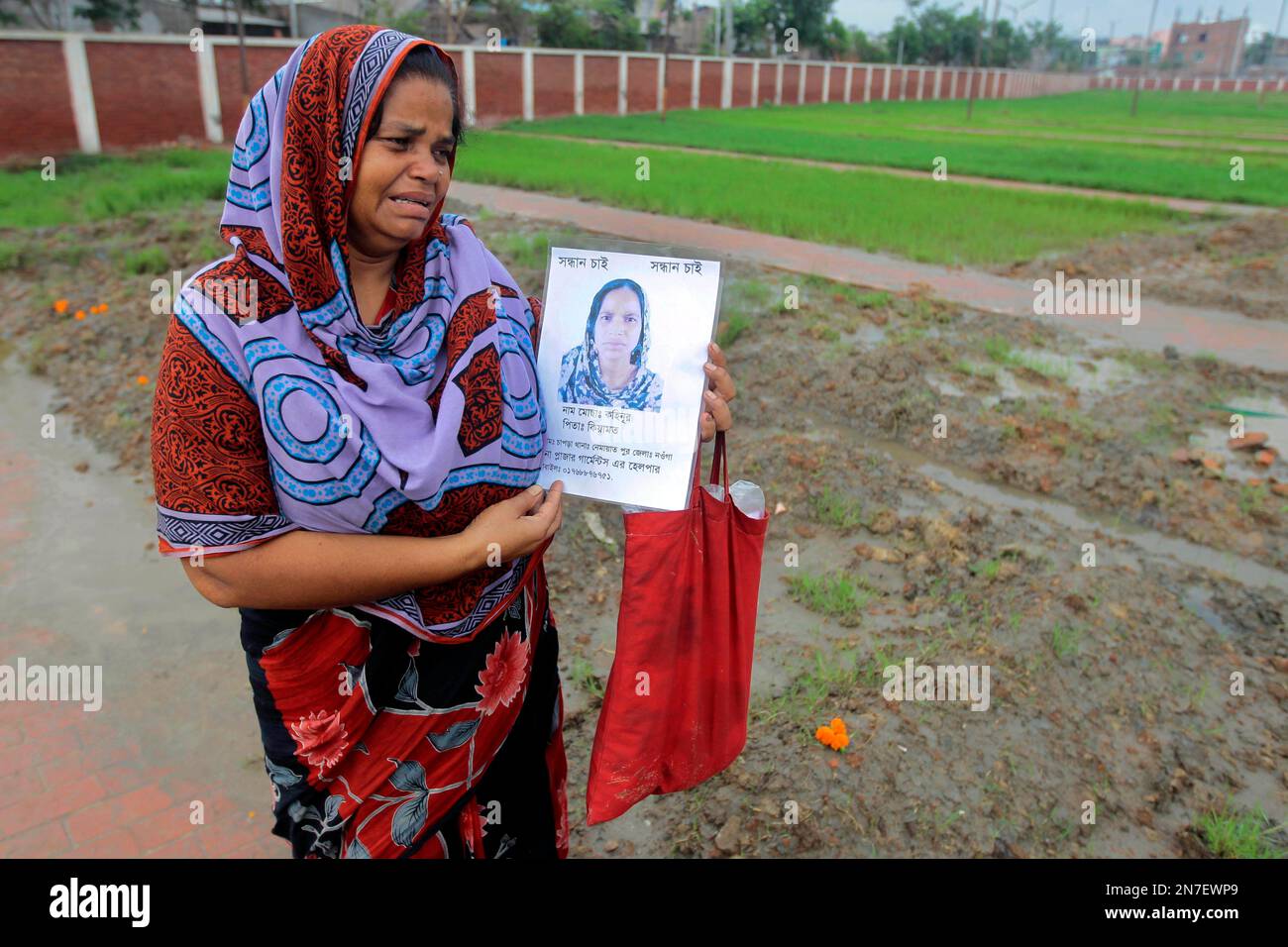 A Bangladeshi woman holds a photograph of her missing relative and cries at a graveyard in Dhaka ...