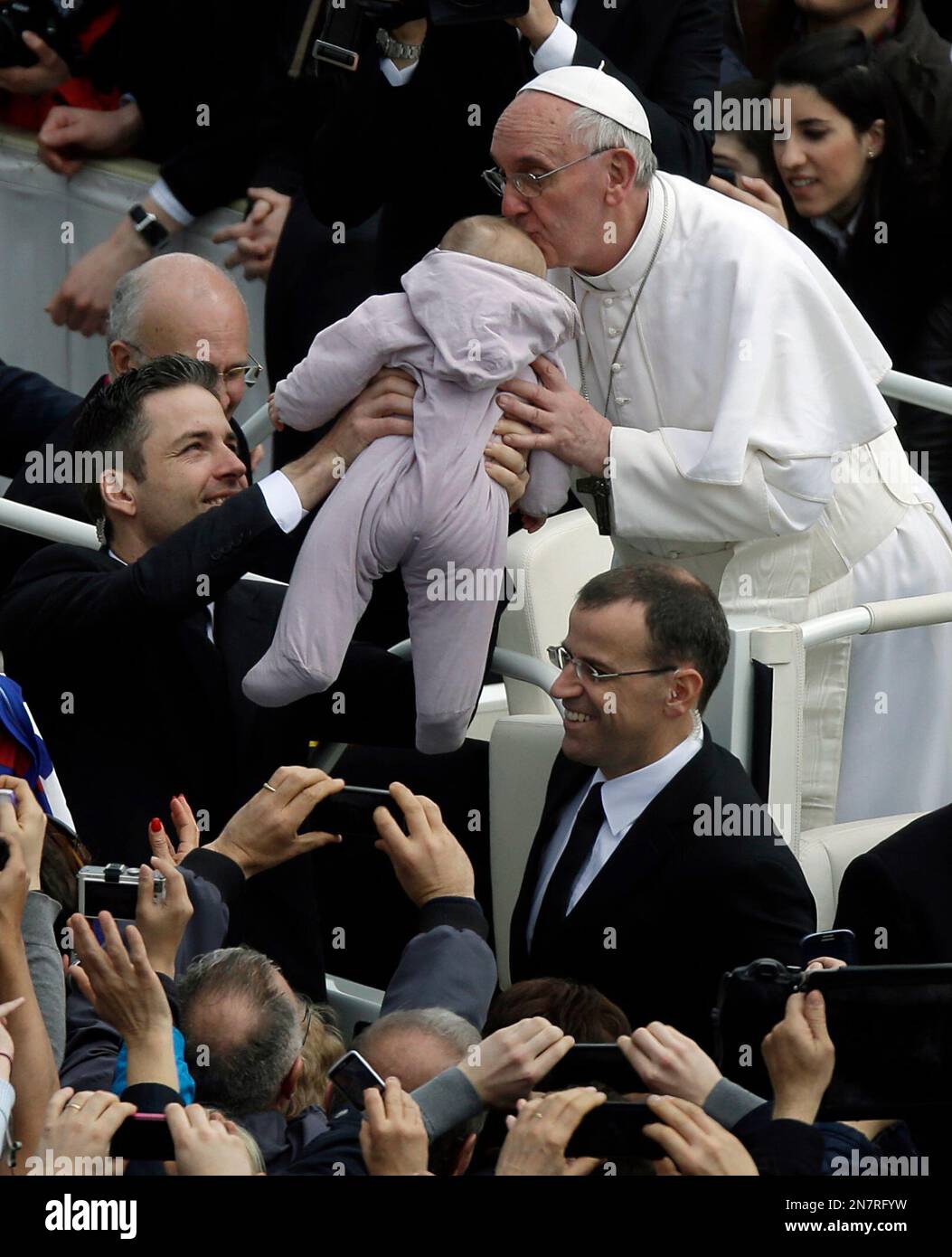 Pope Francis kisses a baby after celebrating his first Easter Mass in ...