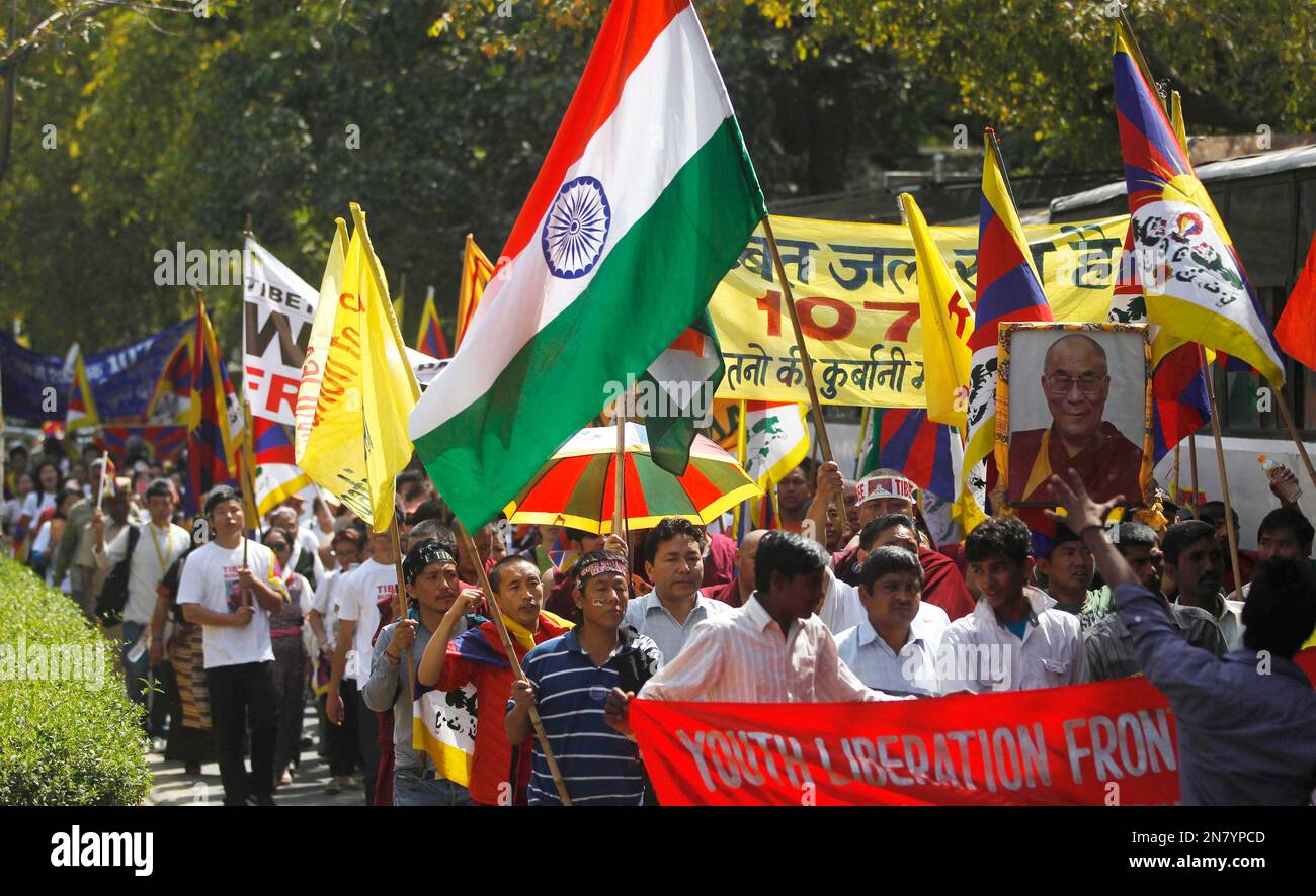 Tibetan Exiles in India carry an Indian flag and a portrait of their ...