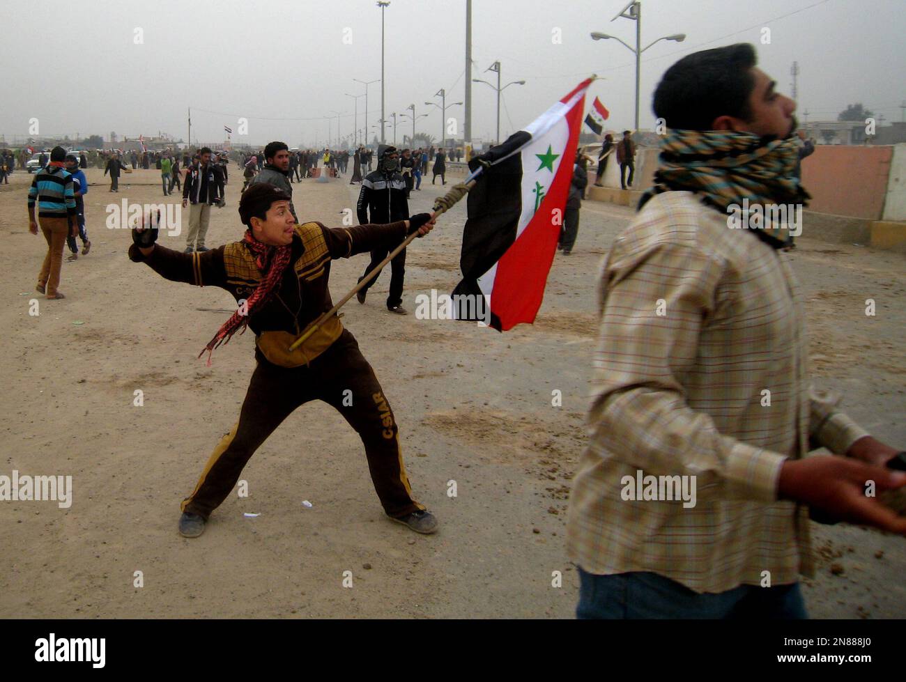 Protesters throw stones towards an Iraqi army checkpoint during clashes ...