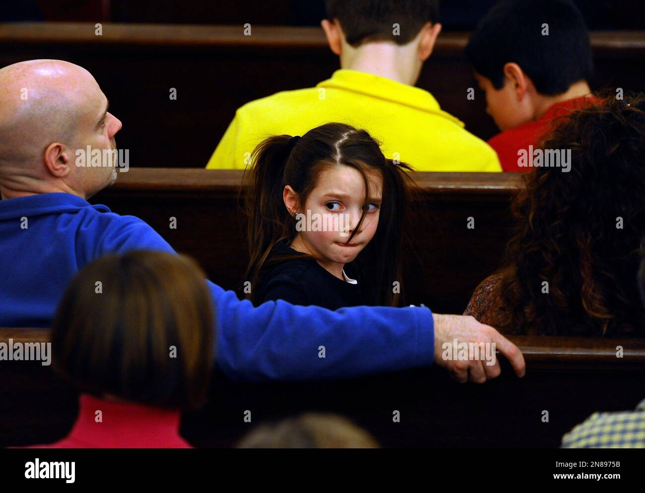 A girl sits with her family in a pew during an interfaith a sermon at ...