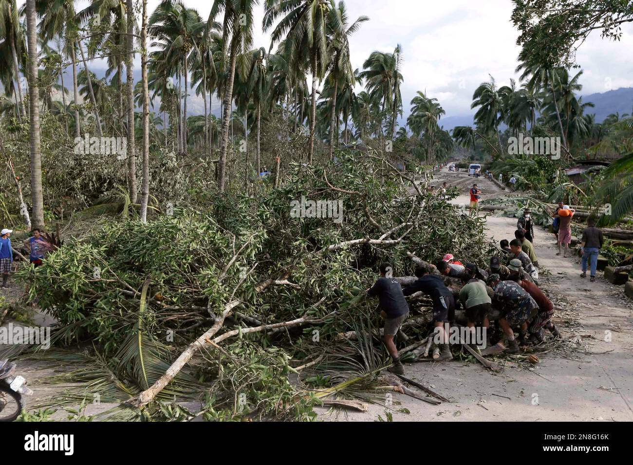 Filipino soldiers and residents work to remove a fallen tree from a ...