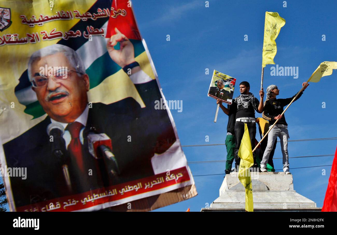 Palestinians wave Fatah flags behind a poster of Palestinian President ...
