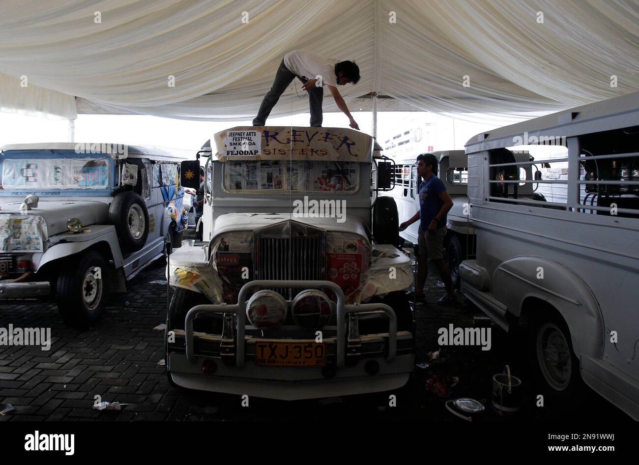 A Filipino student artist spreads paint on a passenger jeepney during a ...