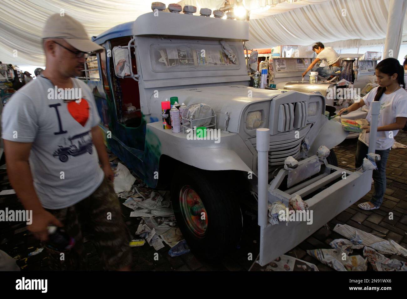 A Filipino man wearing an "I love Jeepney" T-shirt walks by artists ...