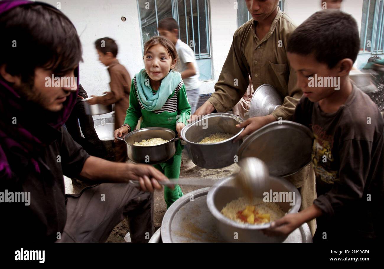 An Afghan cook pours sauce over rice donated by a private charity ...