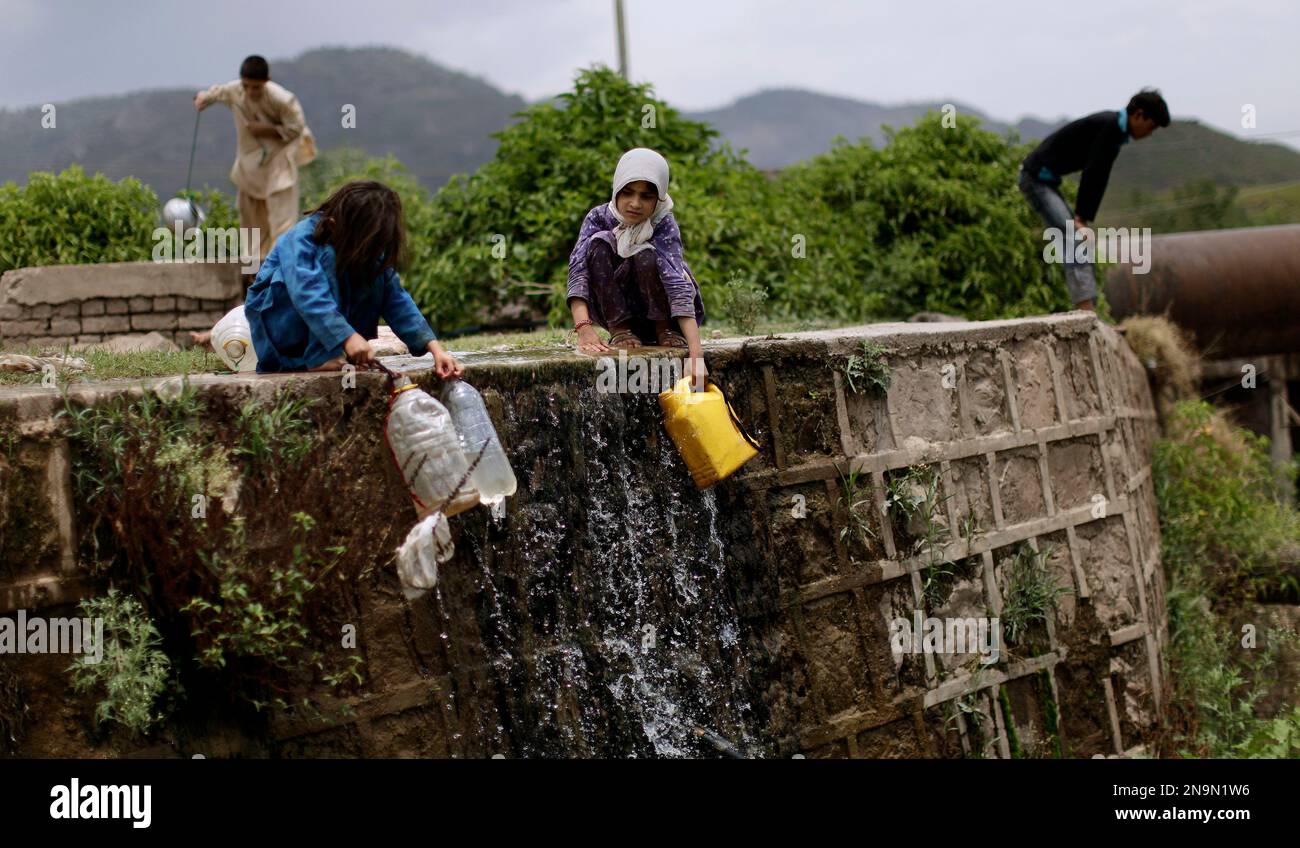 Pakistani girls, center, collect water for drinking from a leaking ...