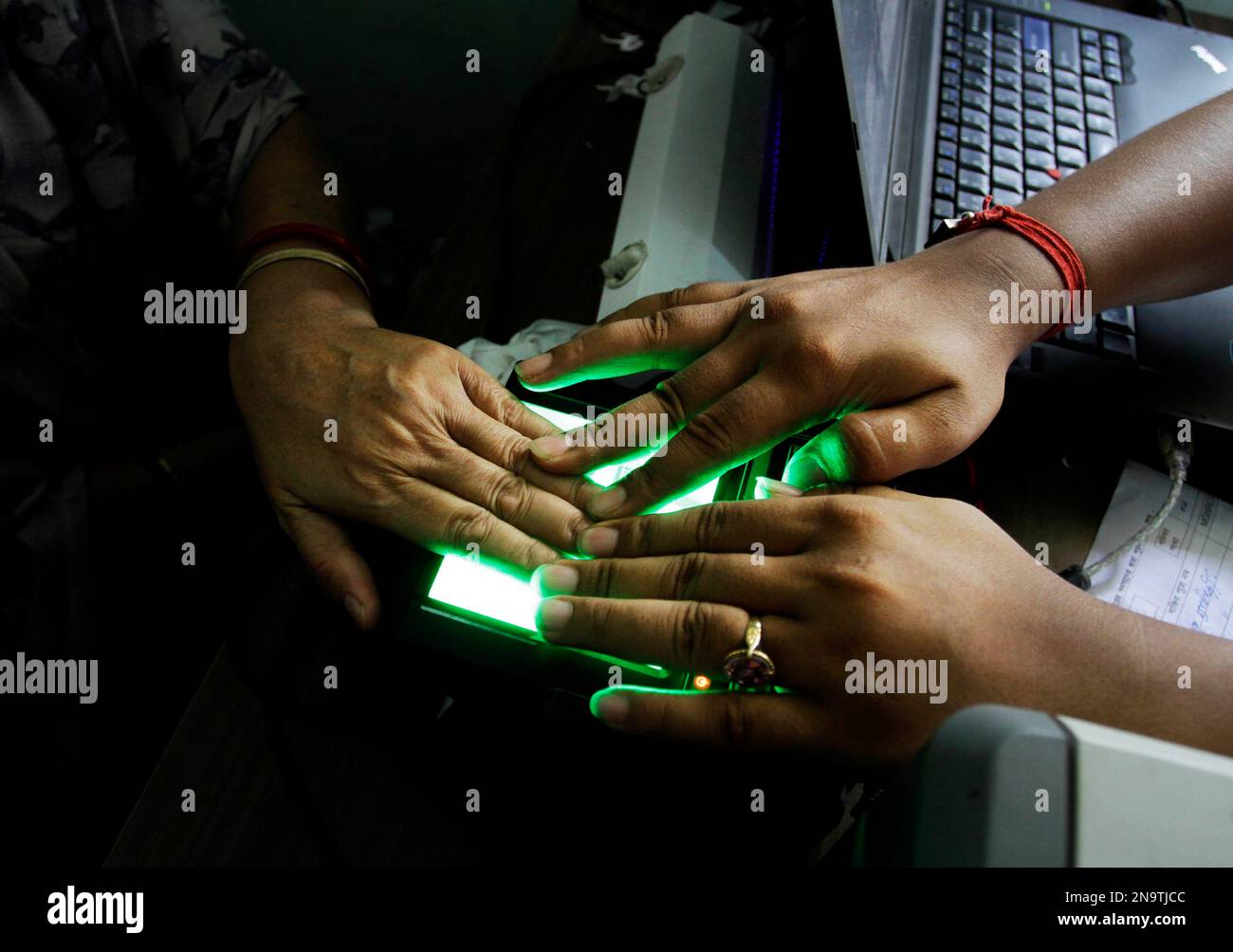 An operator helps an elderly woman scan her fingerprints as she enrolls ...