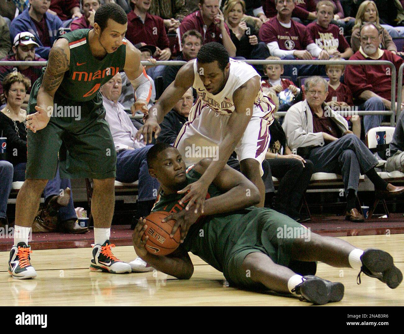 Miami's Reggie Johnson gathers up a loose ball as teammate Trey ...