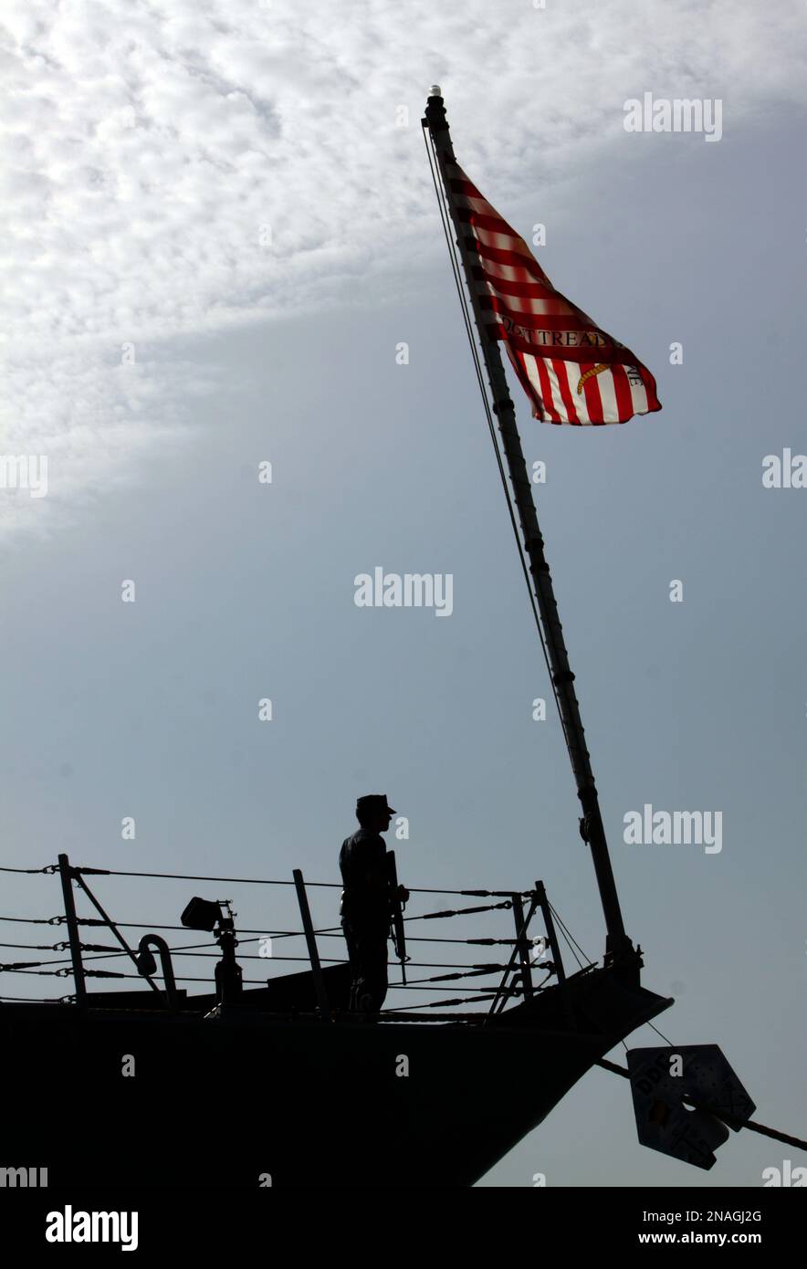 A U.S. Navy sailor is seen by the American flag during a change-of ...