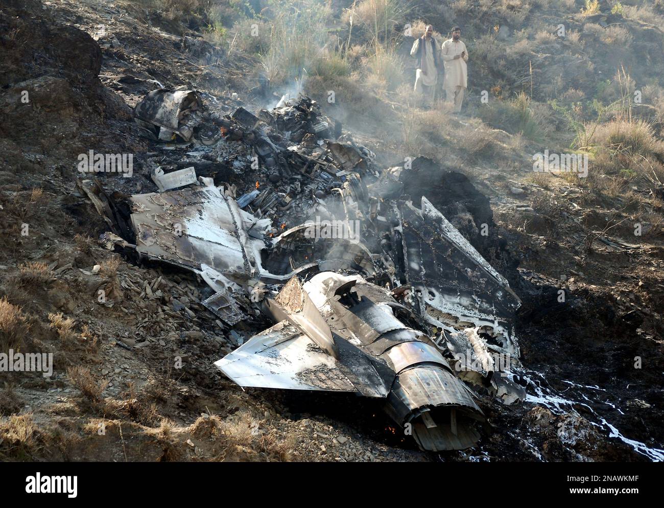 Pakistani villagers stand near wreckage of a Pakistan's air force ...